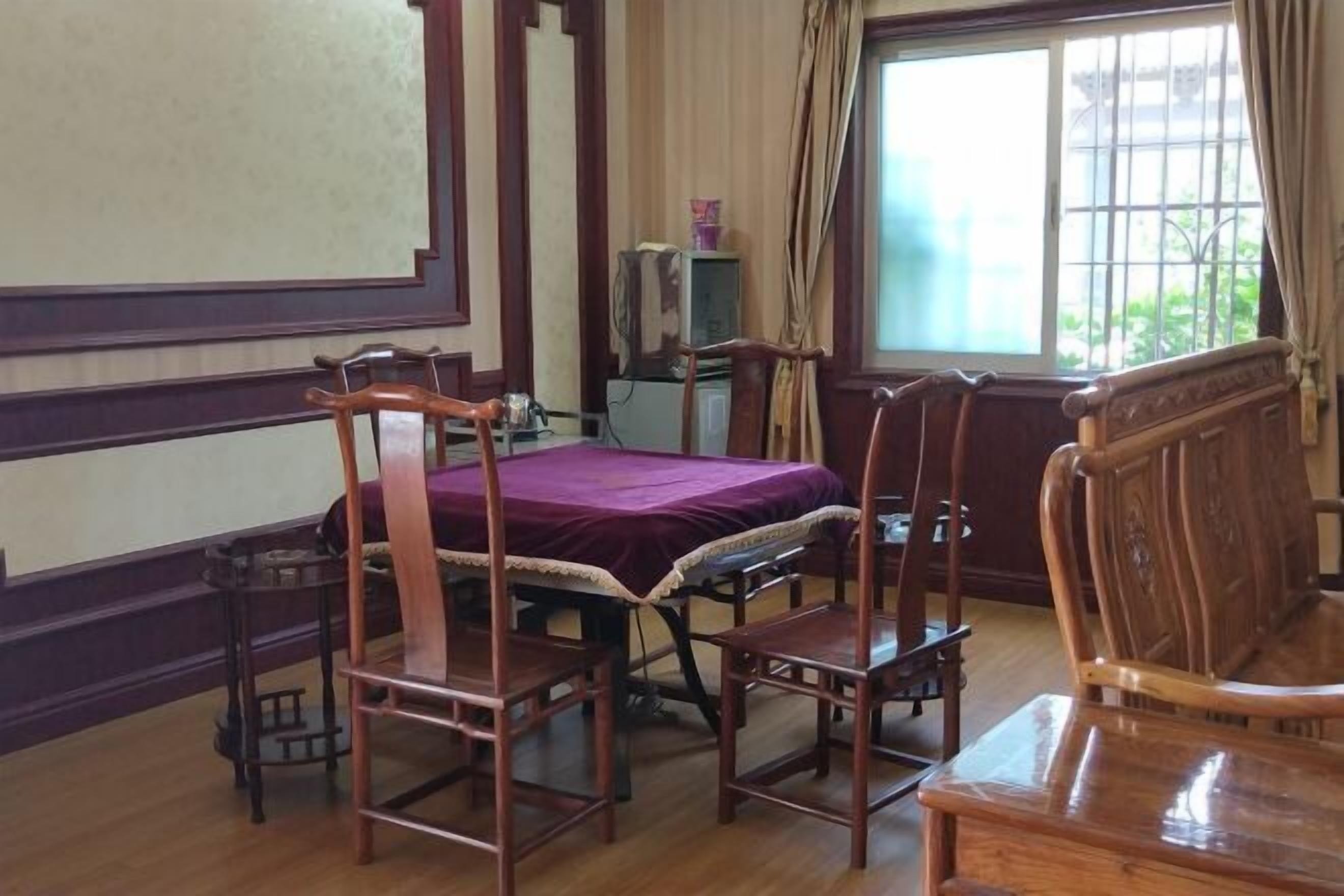 Quarto com uma cama de madeira, uma mesinha e duas cadeiras.