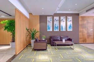 Um lobby moderno com balcão de recepção, área de estar e obras de arte decorativas na parede.