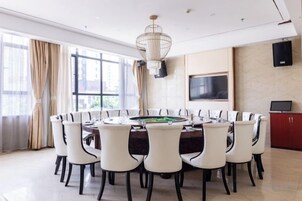 Uma sala de jantar com uma mesa redonda, cadeiras, mesa de bilhar e uma tela de televisão.