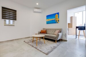 Uma sala de estar moderna com um sofá, uma mesa redonda pequena e um quadro na parede.