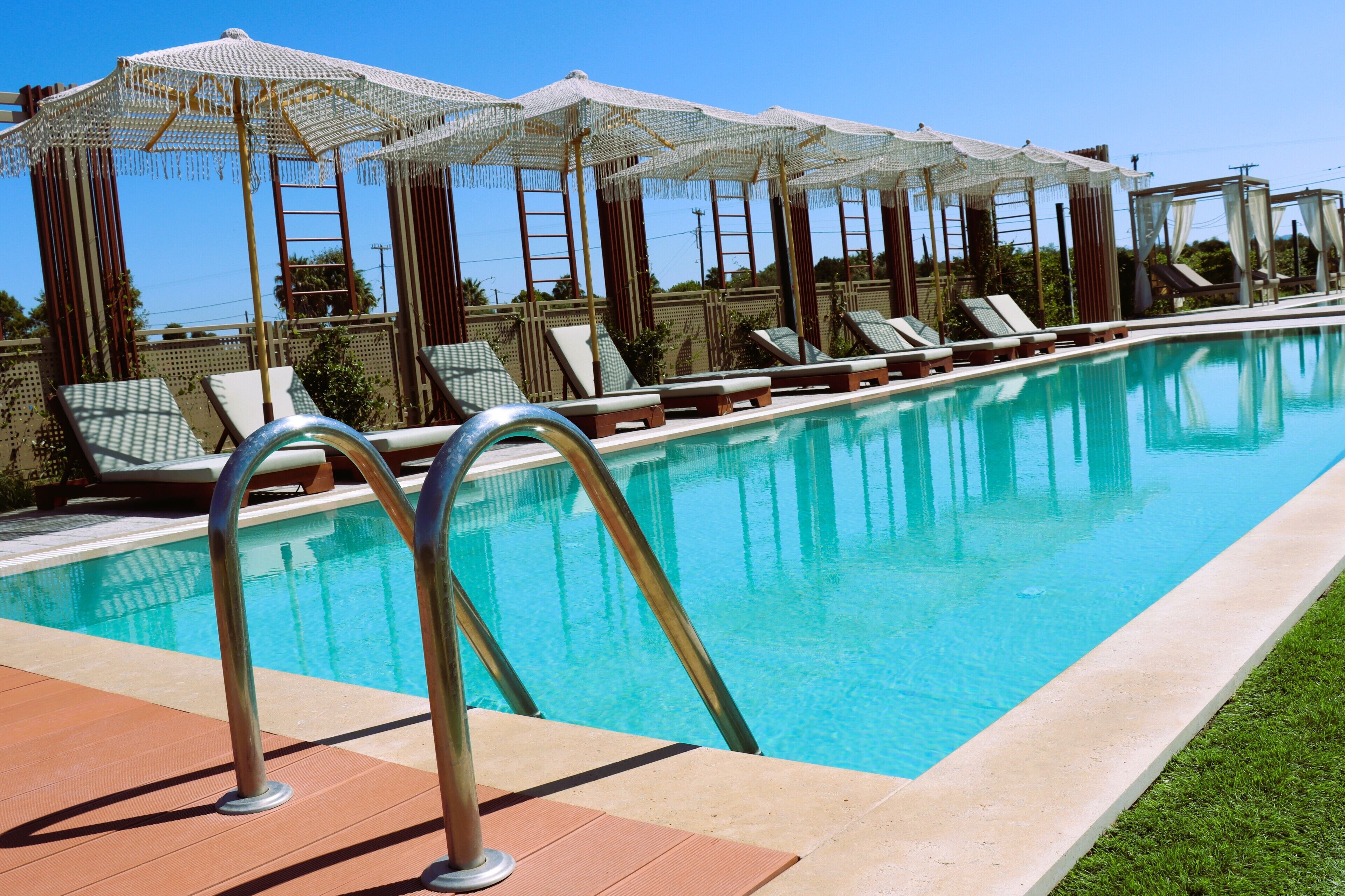 Uma piscina com espreguiçadeiras e guarda-sóis.