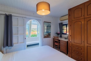 Quarto com cama, escrivaninha, cadeira, espelho e guarda-roupa.