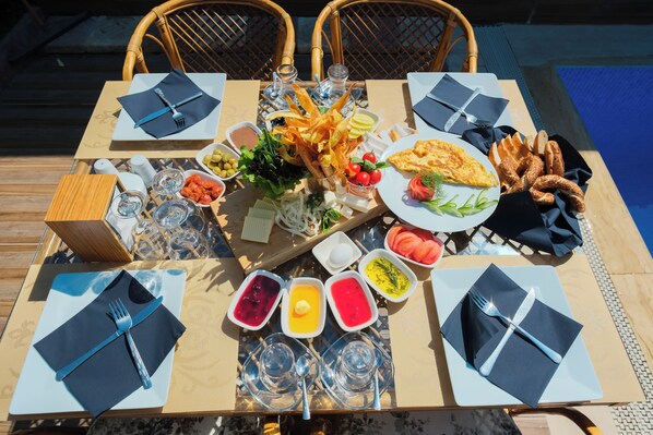 Uma mesa posta para refeição, com diversos pratos, bebidas e acompanhamentos.