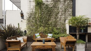 Um deck de madeira com um sofá, uma mesa de centro e um vaso de plantas.