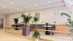 Uma área de recepção moderna com espaço de estar, balcão de atendimento e plantas em vasos.