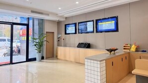 Uma área de recepção moderna com um painel de exibição digital, um vaso de planta e piso ladrilhado limpo.