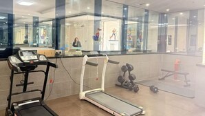 Uma academia com esteiras, halteres e equipamentos de ginástica.