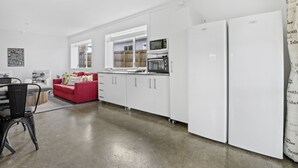 Uma cozinha moderna com armários brancos, um sofá vermelho e um espaço de jantar com uma cadeira preta.
