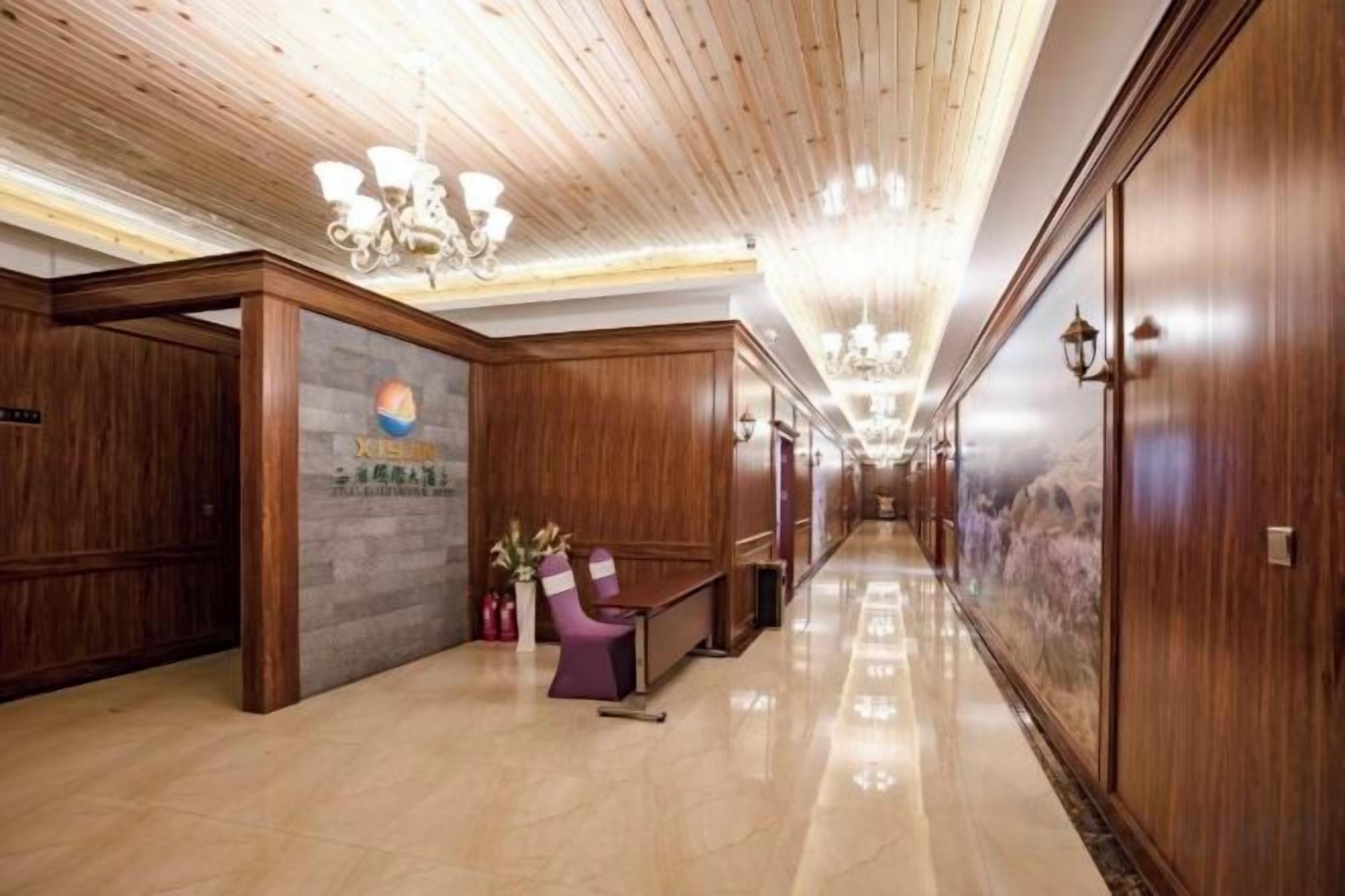 Um saguão de hotel com painéis de madeira, uma mesa de recepção e um candelabro.