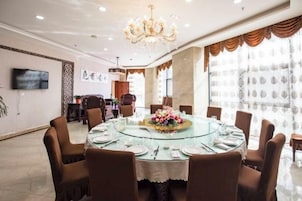 Uma sala de jantar com mesa redonda, cadeiras e lustre.