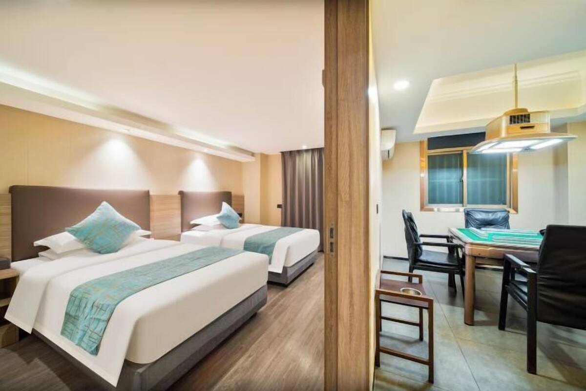 Quarto de hotel com duas camas, uma mesa e uma cadeira.