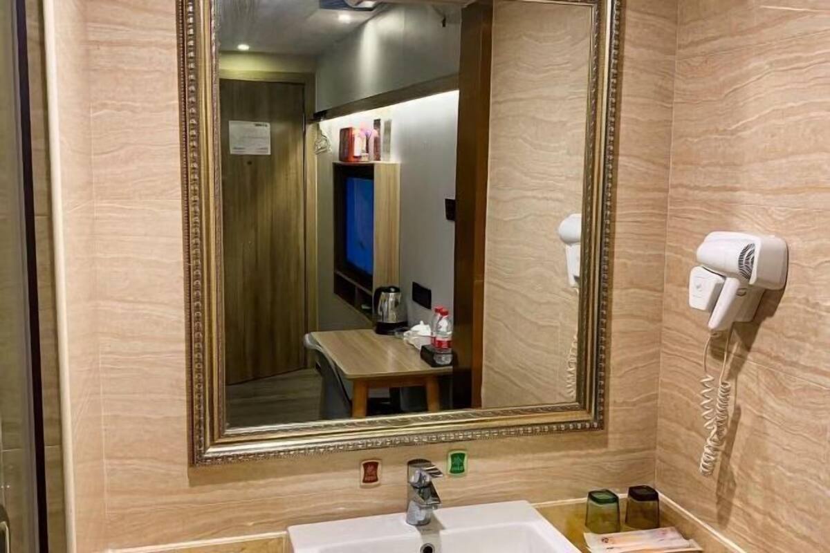 Casa de banho de hotel com um espelho grande, uma pia, um secador de cabelo e um telefone.