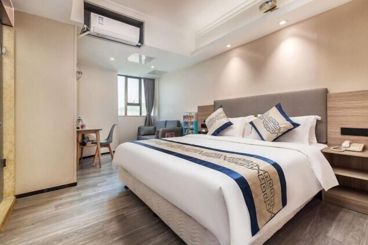 Quarto de hotel com cama, mesa de cabeceira e escrivaninha com cadeira.