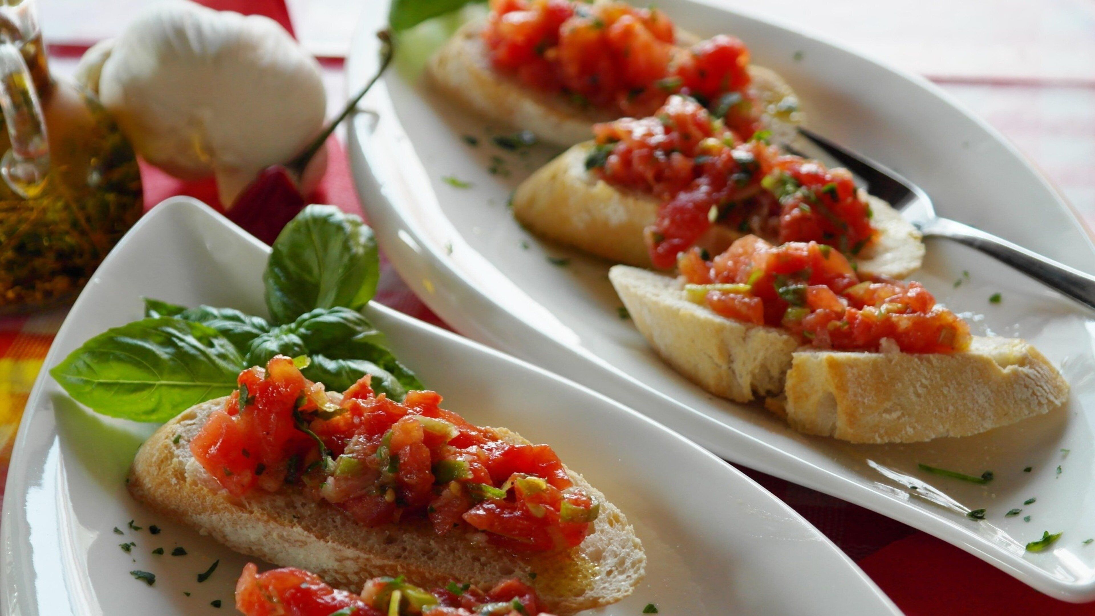 Uma tábua de bruschetta coberta com tomate e manjericão.