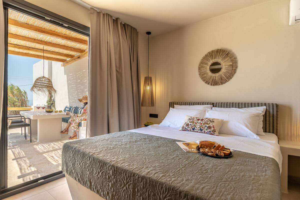 Quarto com cama, mesa de jantar e vista para o exterior.