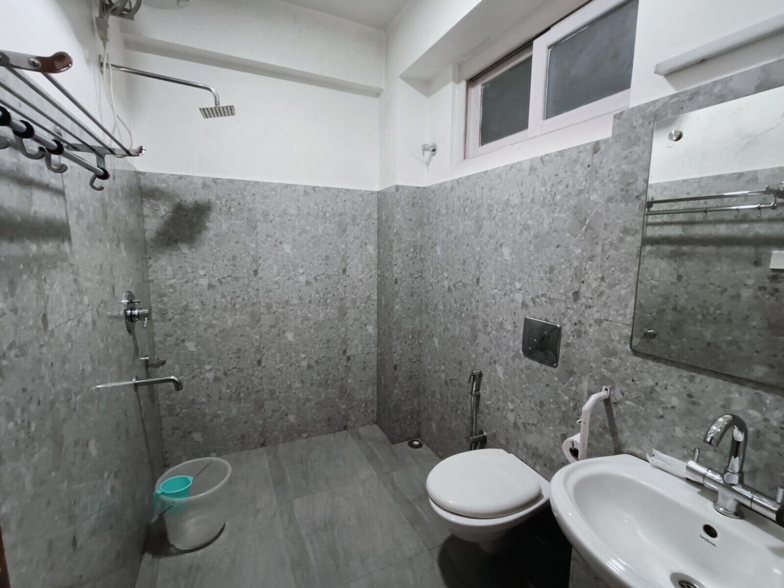 Casa de banho compacta com sanita, lavatório e chuveiro.