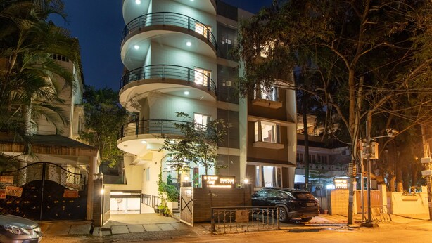 Um edifício com várias andares, varandas, portão e um carro estacionado.