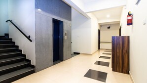 Corredor moderno com escada, extintor de incêndio e porta de madeira.