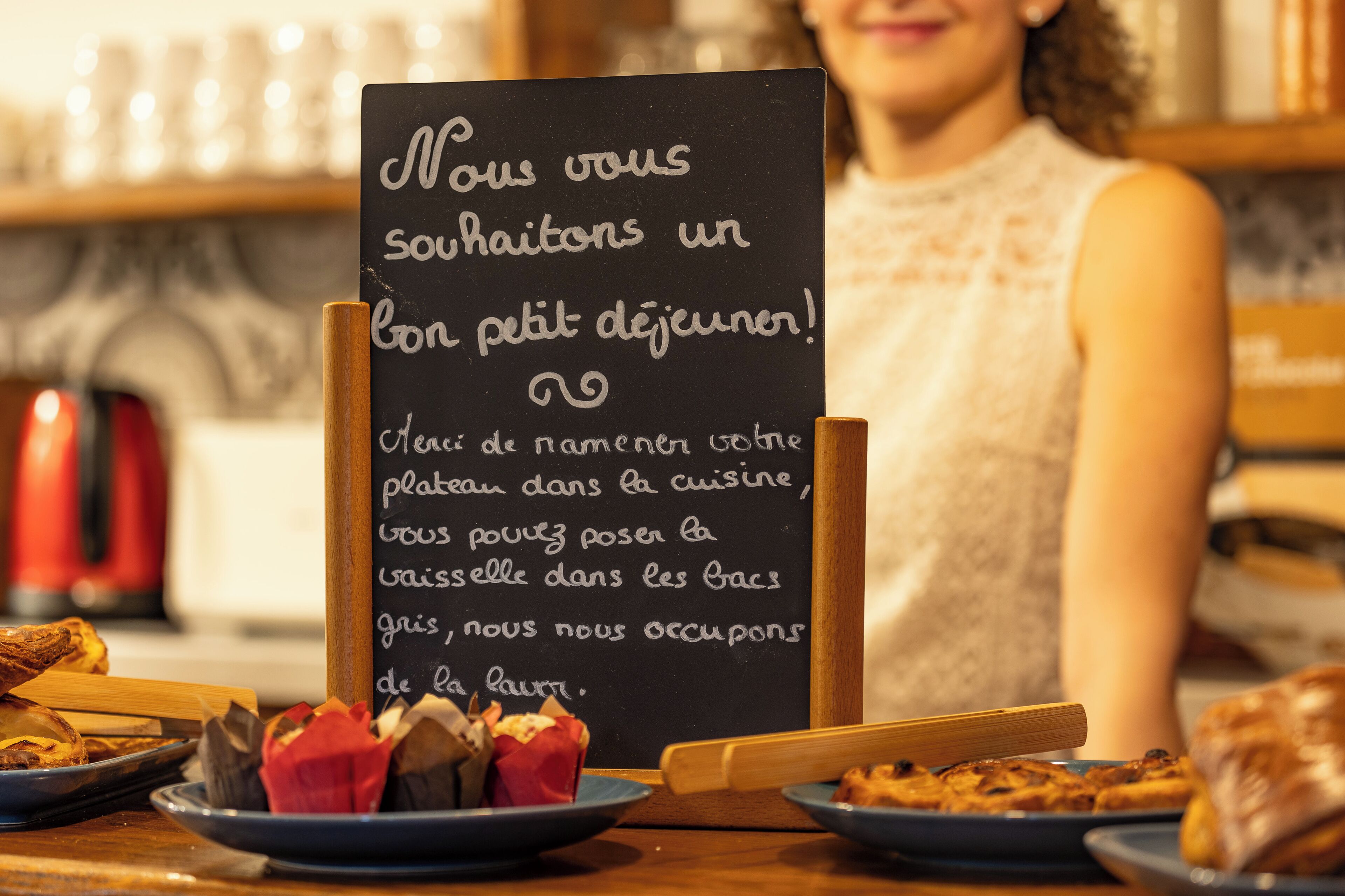 Um menu em lousa em restaurante, com pratos de comida expostos.