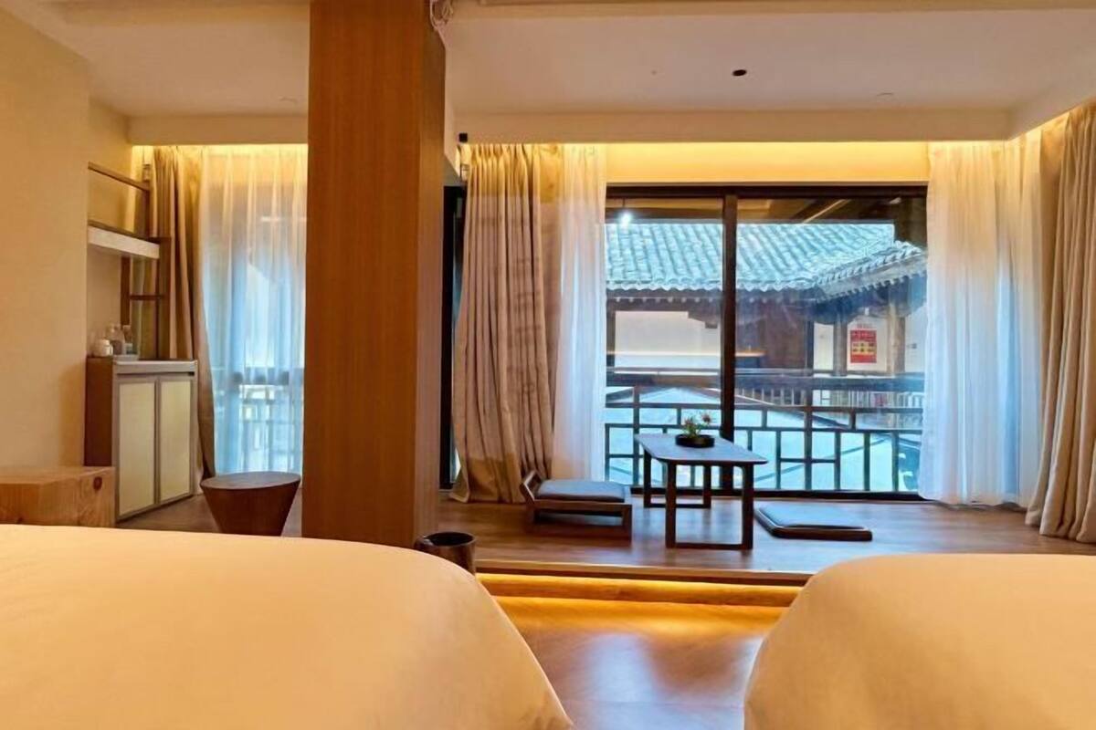 Quarto de hotel com varanda, uma cama, uma mesinha e um espaço para sentar.