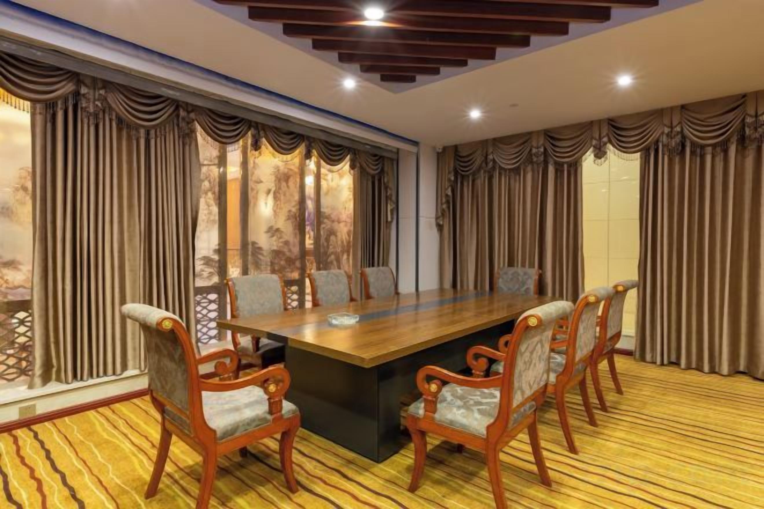 Uma sala de conferências com uma mesa comprida, seis cadeiras e cortinas.