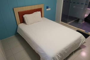 Cama de casal com cabeceira de madeira e roupa de cama branca em quarto com paredes azuis e divisória de vidro.