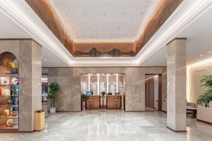 Um saguão de hotel com balcão de recepção, um espelho grande e uma área de estar.