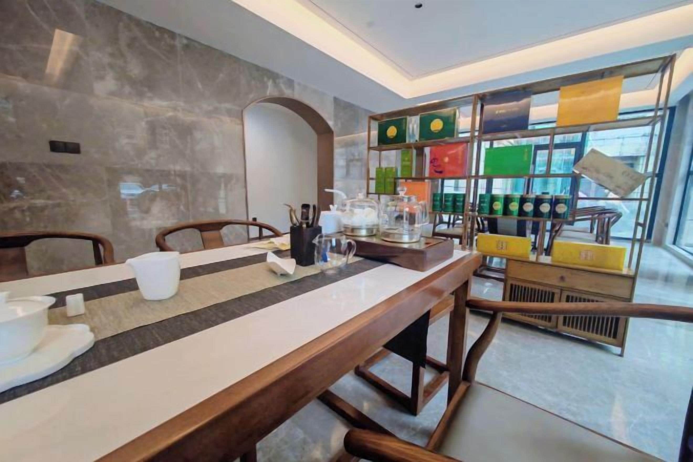 Uma sala de jantar com parede de mármore, uma mesa de madeira comprida e uma estante com diversos objetos.