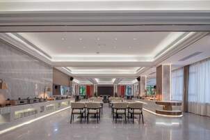 Um hall amplo com balcão de recepção, área de estar e uma grande janela que oferece iluminação natural.