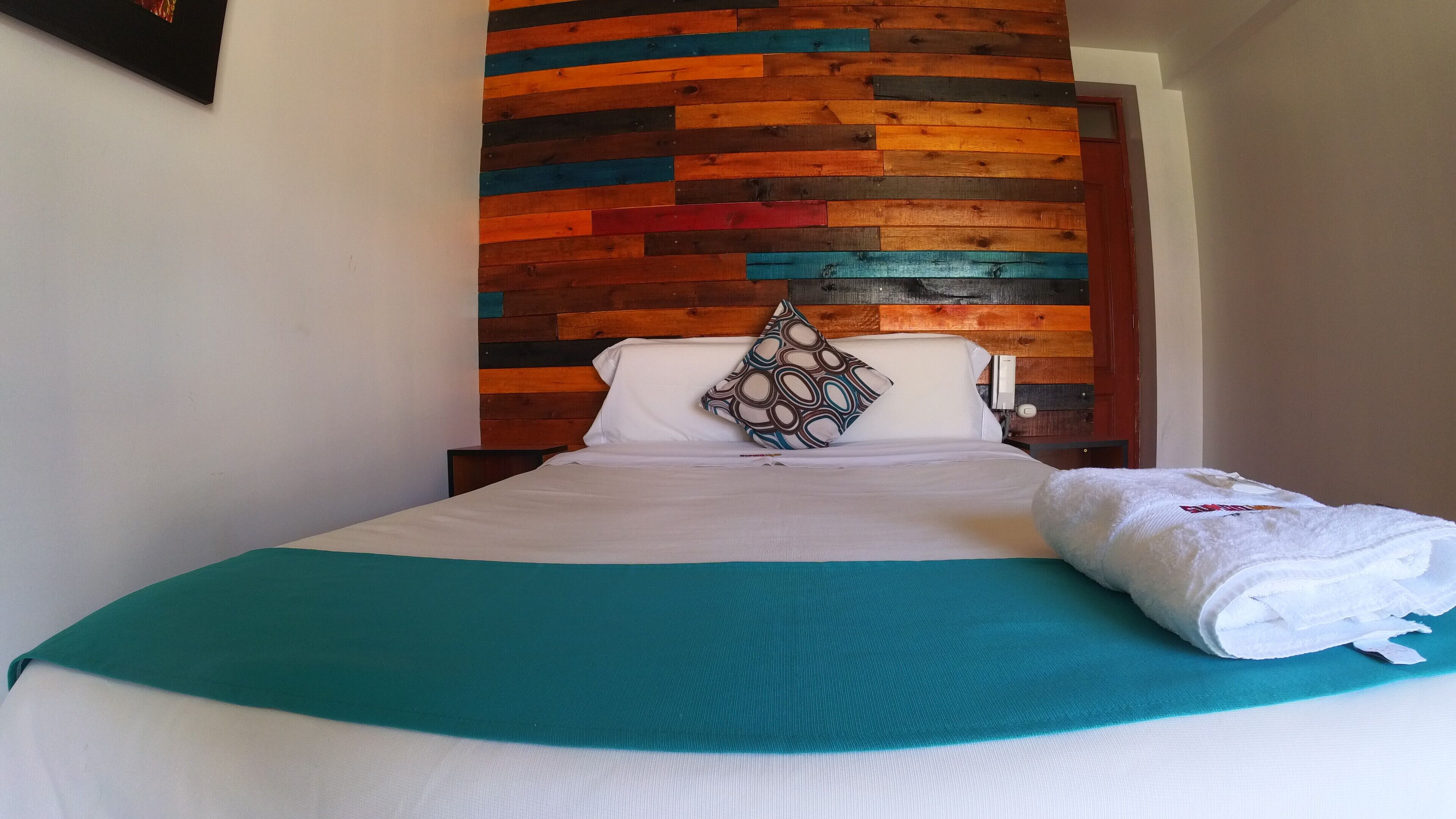 Uma cama bem arrumada com um cobre-leito verde-água e um travesseiro branco com padrão geométrico.