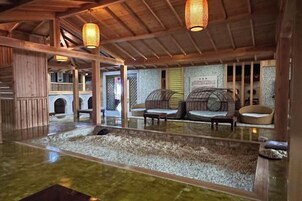 Interior tradicional em estilo japonês, com tatames, vigas de madeira baixas e um espaço de estar com almofadas.