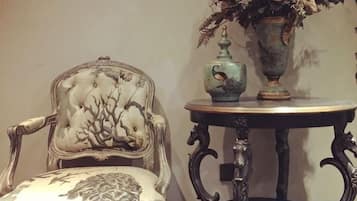 Uma cadeira antiga com padrão floral e uma mesa com um vaso.
