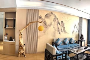 Uma sala de estar moderna com um sofá, mesa de centro e elementos decorativos como uma escultura de árvore e um adorno pendurado.