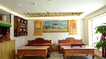 Quarto tradicional com sofá de madeira, uma mesa e uma estante.