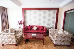 Uma sala de estar com um sofá vermelho, duas poltronas estampadas e uma mesa de centro de madeira.