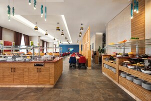 Restaurante estilo buffet com diversos pontos de serviço, balcões de madeira e uma variedade de alimentos expostos.