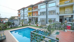 Um edifício residencial com vários andares, piscina, área de estar externa e varandas.