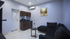 Um espaço compacto com cozinha compacta, um sofá preto, uma mesa pequena e um quadro na parede.