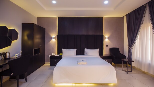 Quarto de hotel moderno com uma cama grande, uma escrivaninha, uma cadeira e um guarda-roupa.
