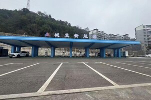 Um estacionamento com cobertura azul, um carro branco e um edifício com sinalização em língua estrangeira.