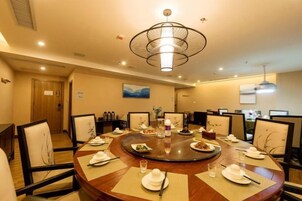 Uma sala de conferência com uma mesa redonda, cadeiras e um lustre.