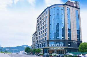 Um hotel de vários andares com fachada curva, grandes janelas e entrada visível com sinalização.