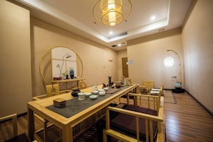Uma sala de jantar com uma mesa comprida, cadeiras e um espelho grande.