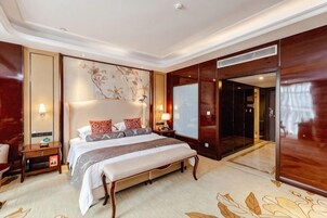 Quarto de hotel com cama grande, mesas de cabeceira, espelho e guarda-roupa.