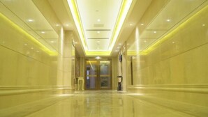 Um corredor amplo e bem iluminado, com piso lustroso e design moderno no teto.