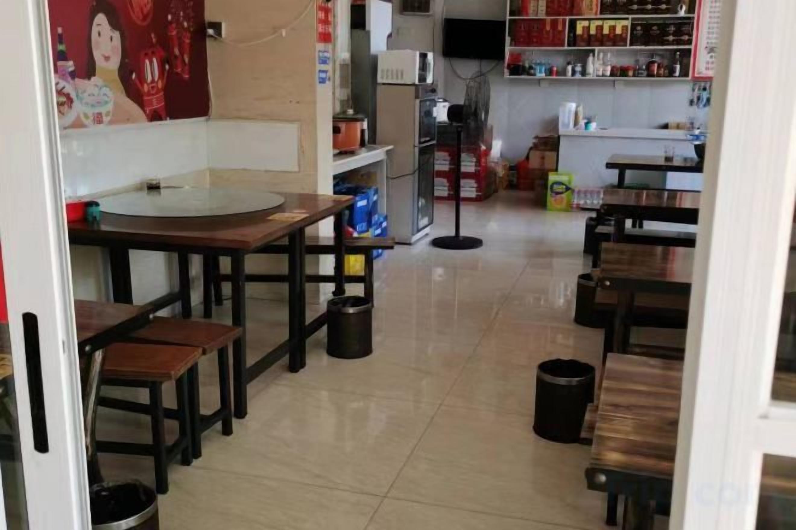 Interior de restaurante com mesas, cadeiras, balcão e uma tela de televisão.