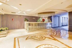 Uma área de recepção de hotel com balcão, piso estampado e design de interiores moderno.