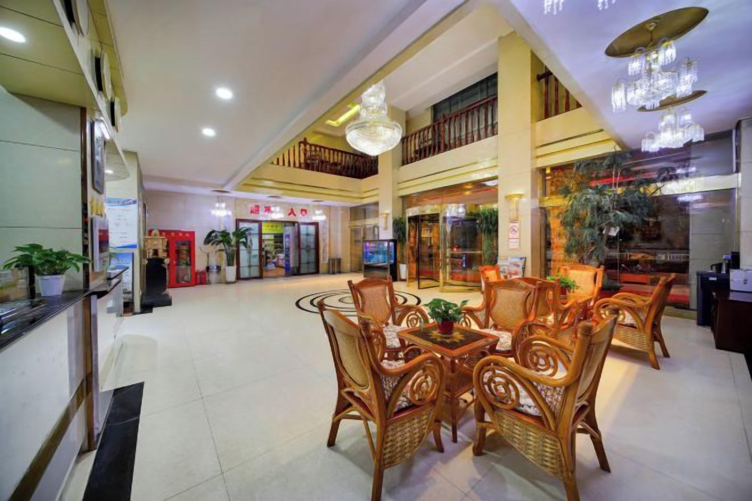 Um hall espaçoso com teto alto, área de estar central com móveis de vime e entrada visível para um restaurante.