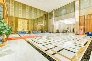 Um hall amplo com piso de mármore, áreas de estar e uma grande parede decorativa.