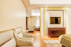 Quarto de hotel com sofá, cama, armário e televisão.